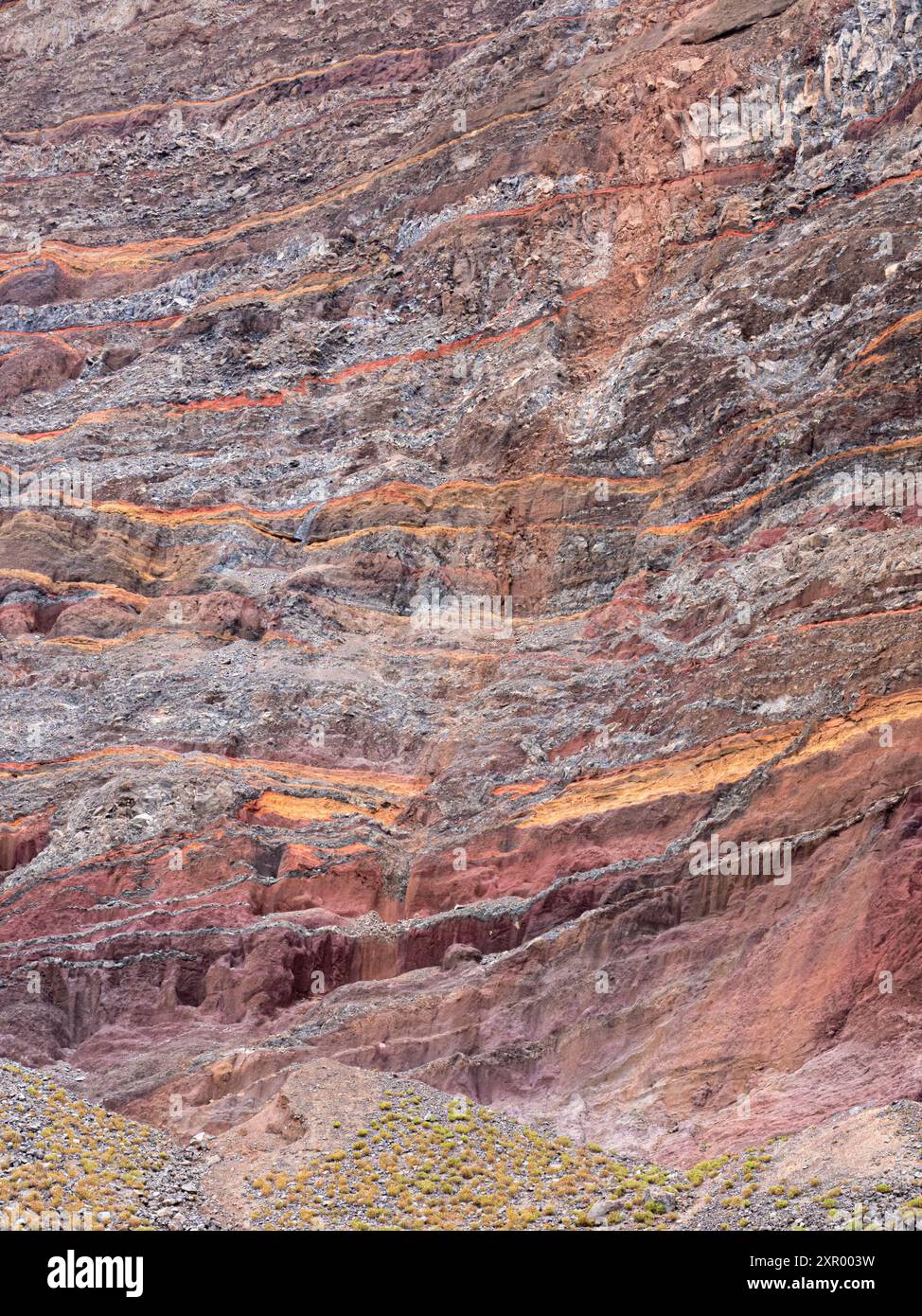 Eroded lava cliff with coloured tufts and horizontal basaltic layers ...