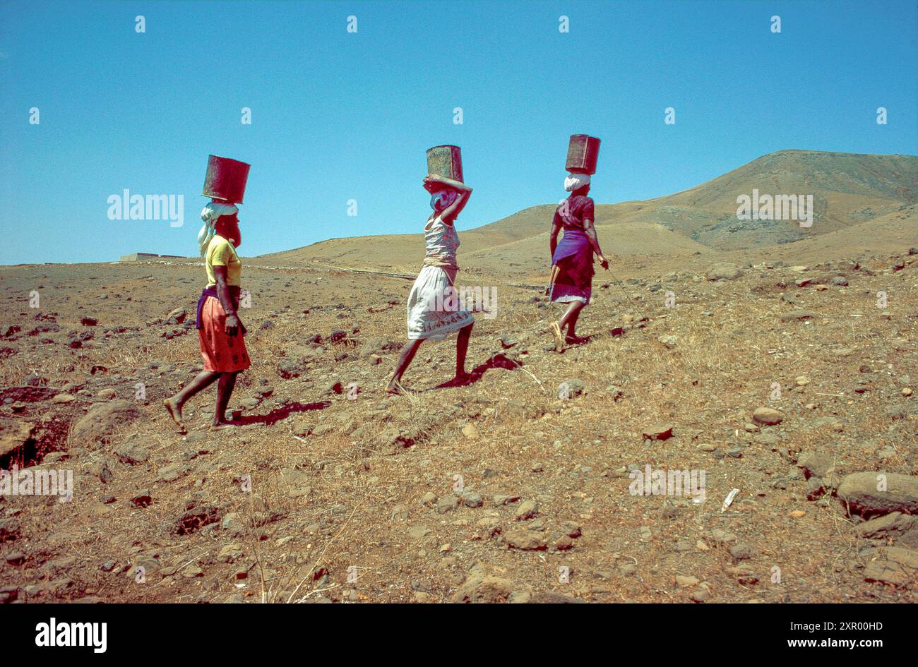 Cape Verde, Sao Tiago. Women fetching water walking on the dry hills of ...
