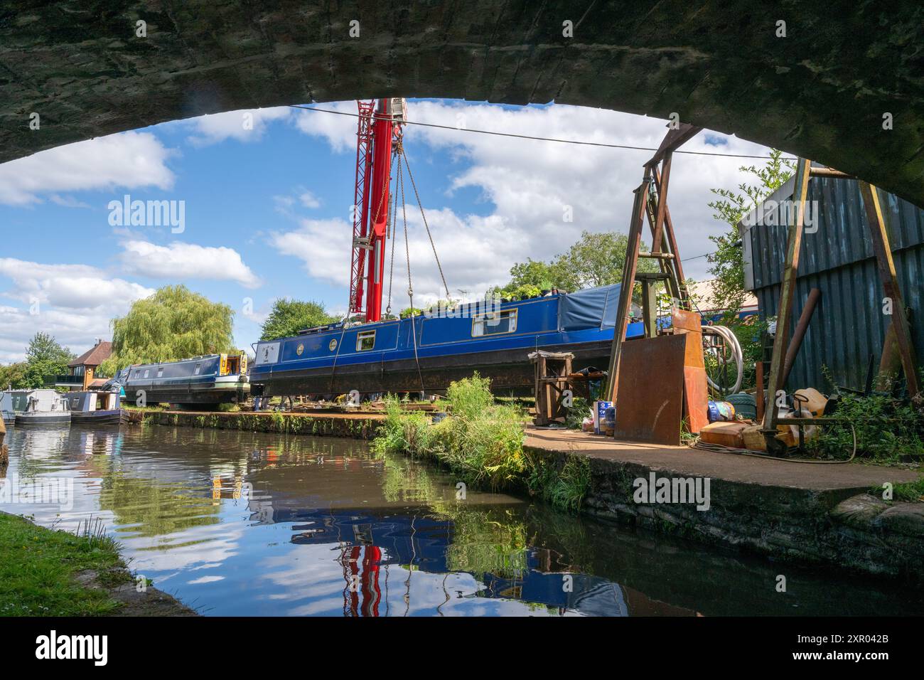 Old narrowboat being lifted by a crane out of the canal and into a boat ...