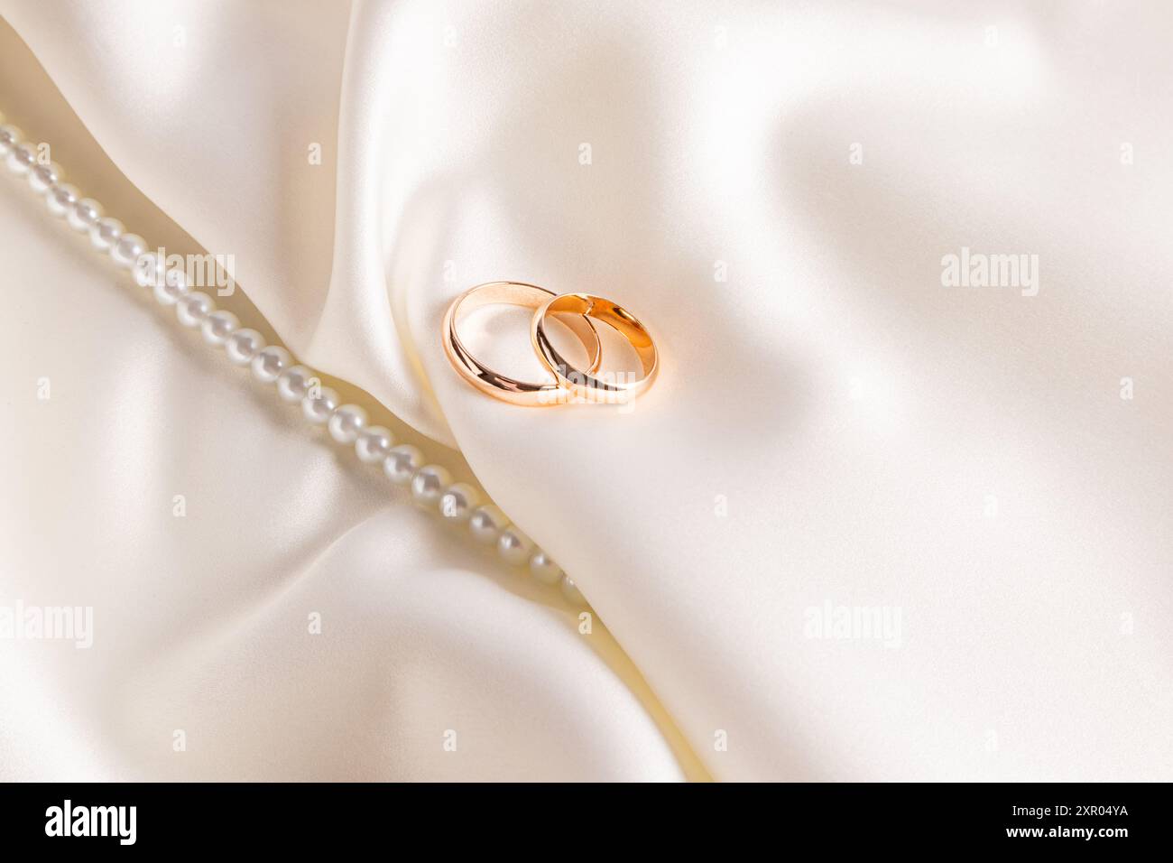 Two classic gold wedding rings on a beige satin background with ...