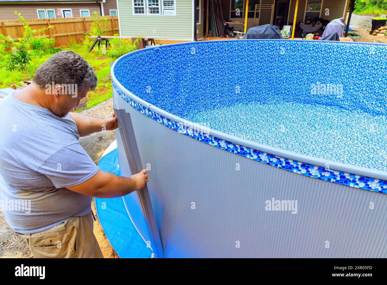 Worker is in process of installing metal frame of an above ground pool ...