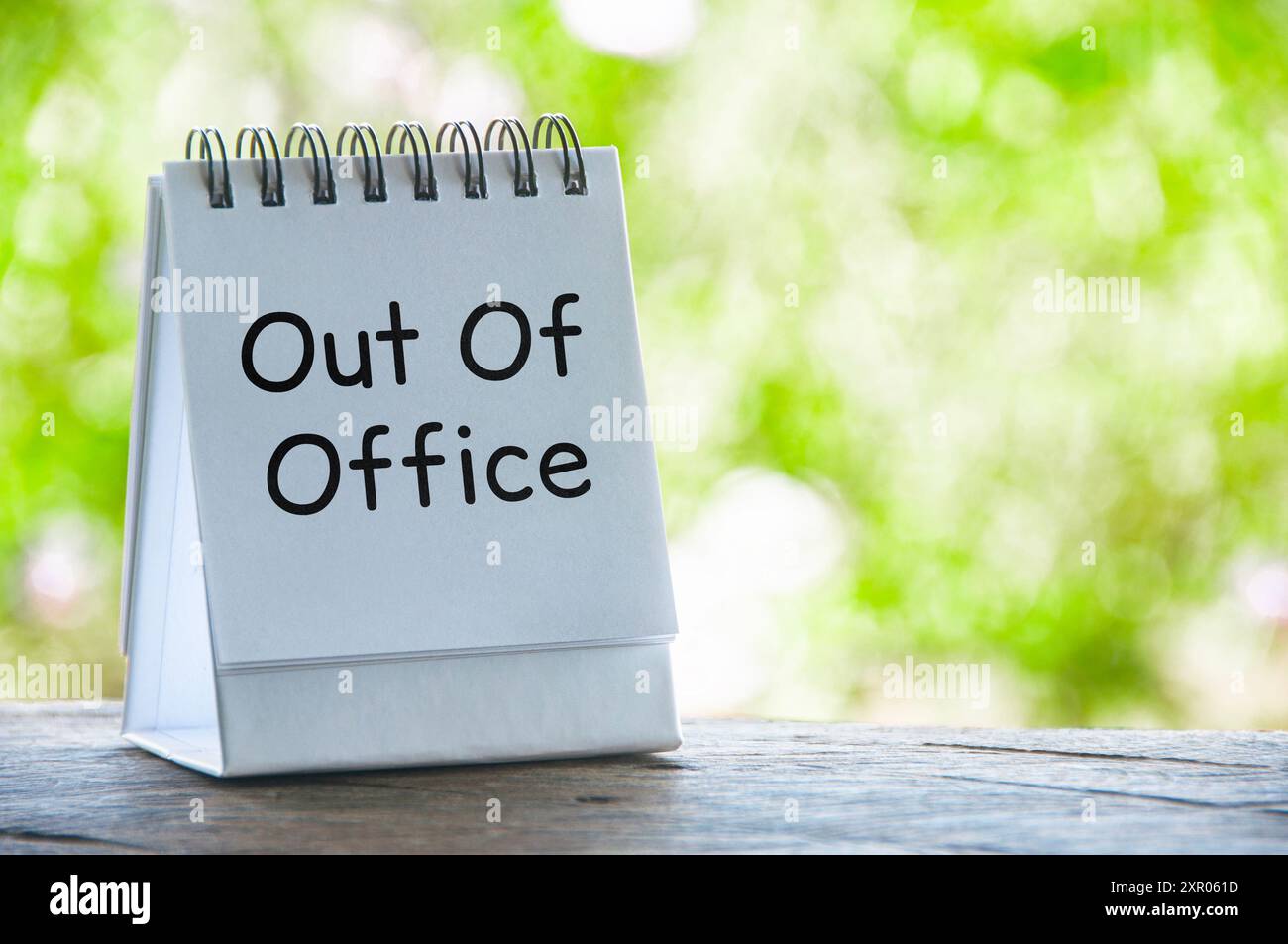 Out Of Office text on white notepad with bright green nature background ...
