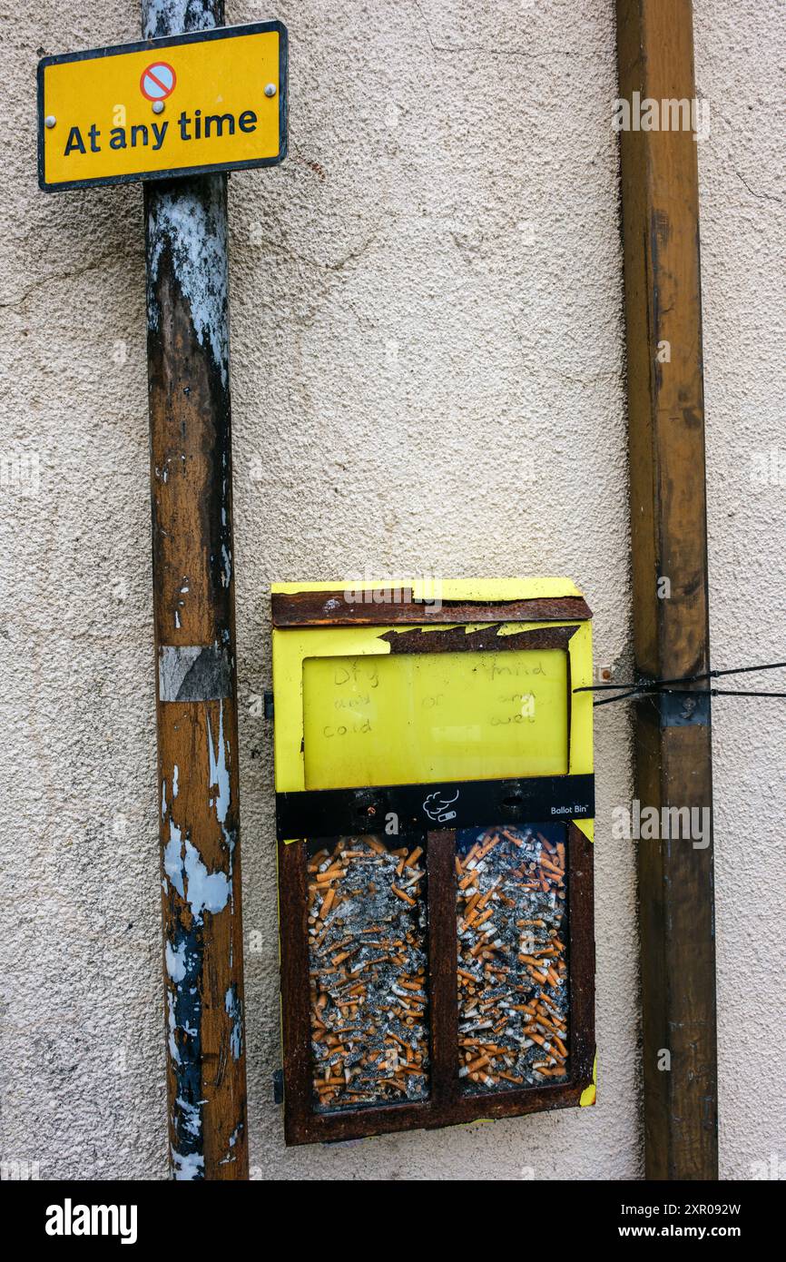 A full cigarette bin mounted on a wall in Brecon town centre, Powys ...
