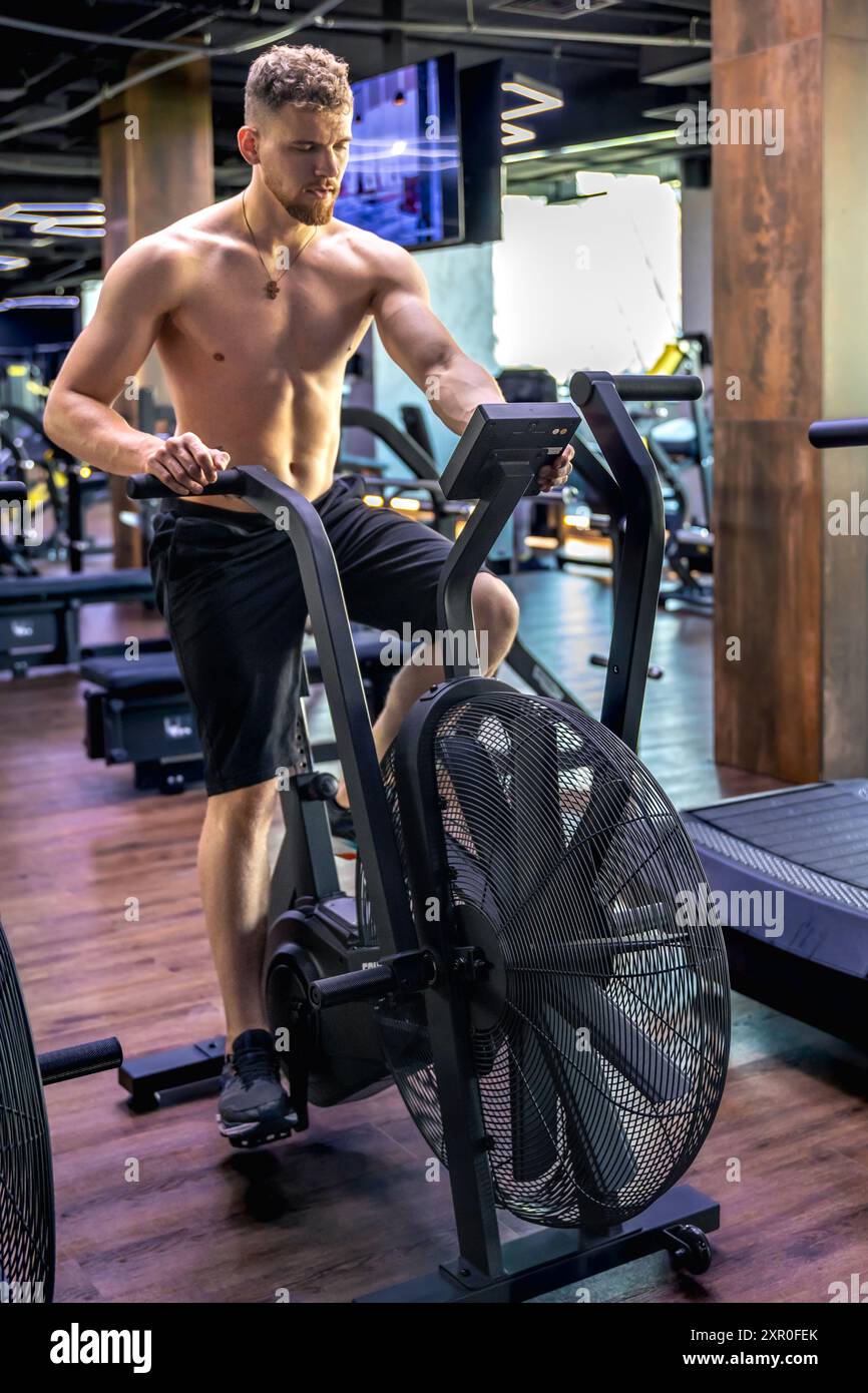 Exercises on an air bike in full height. Young athlete in the gym Stock ...