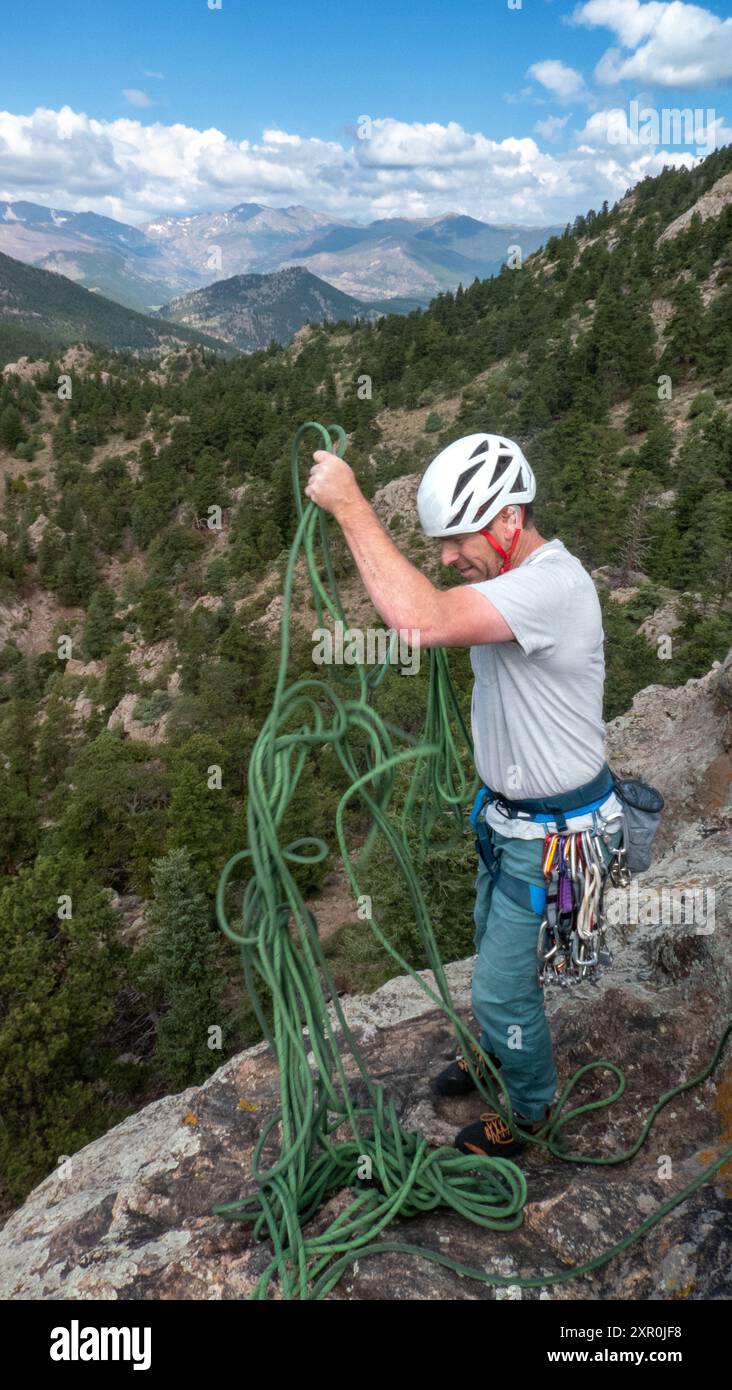 Single adult male climber coils a climbing rope to prepare for ...