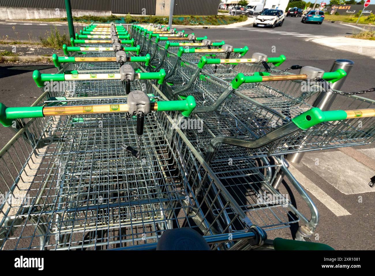 A row of shopping carts with green handles neatly arranged in an ...