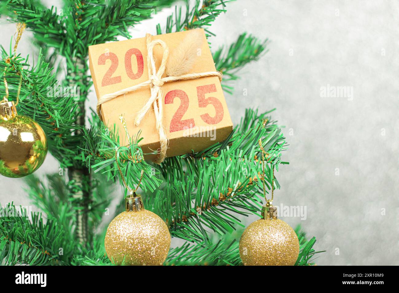 Gift box with 2025 written in red on top of Christmas tree decorated ...