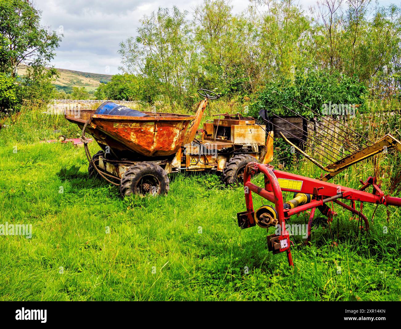 Aged farming equipment sits idle in a lush green field, surrounded by ...