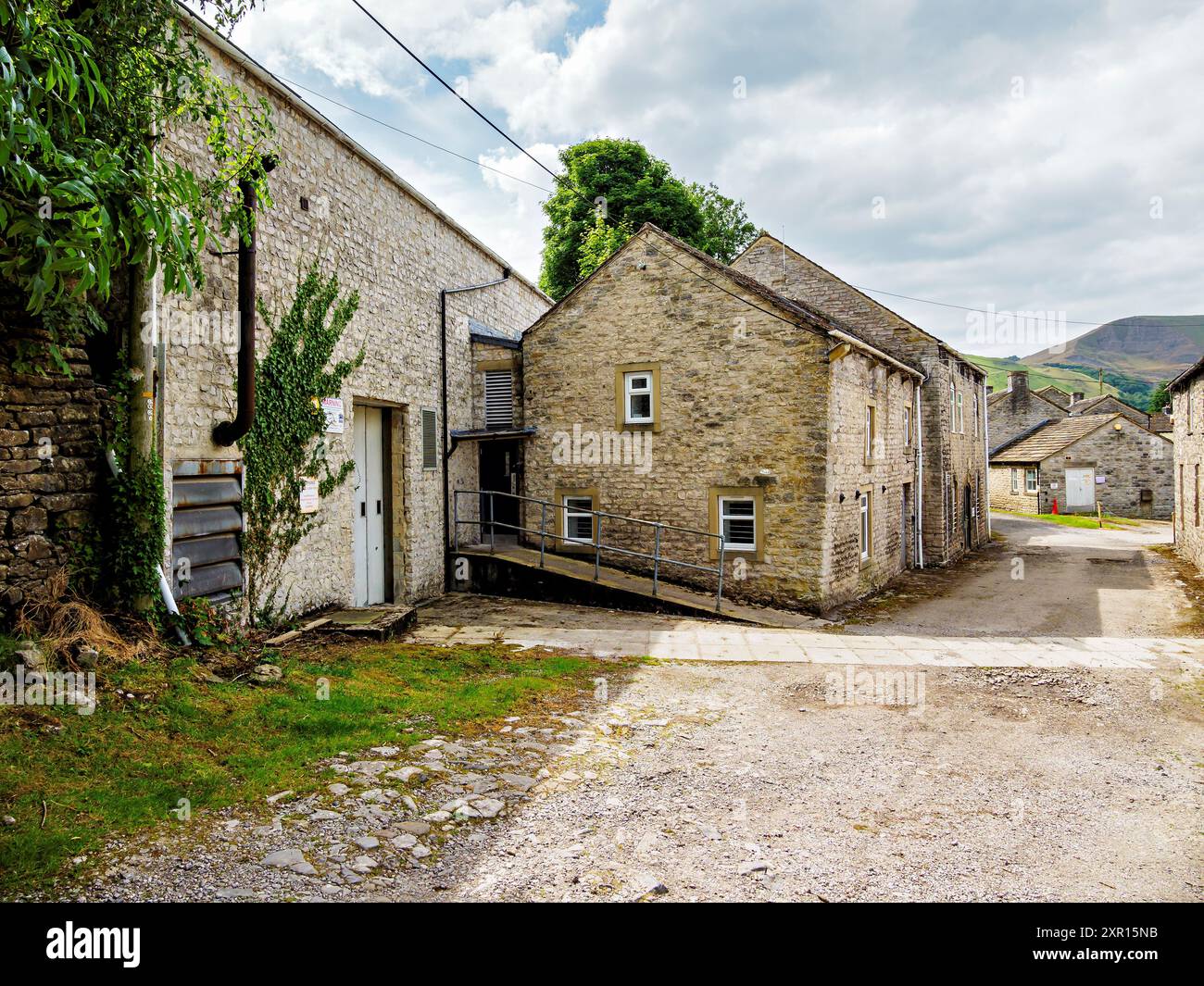 Quaint stone buildings in a serene countryside setting under a cloudy ...