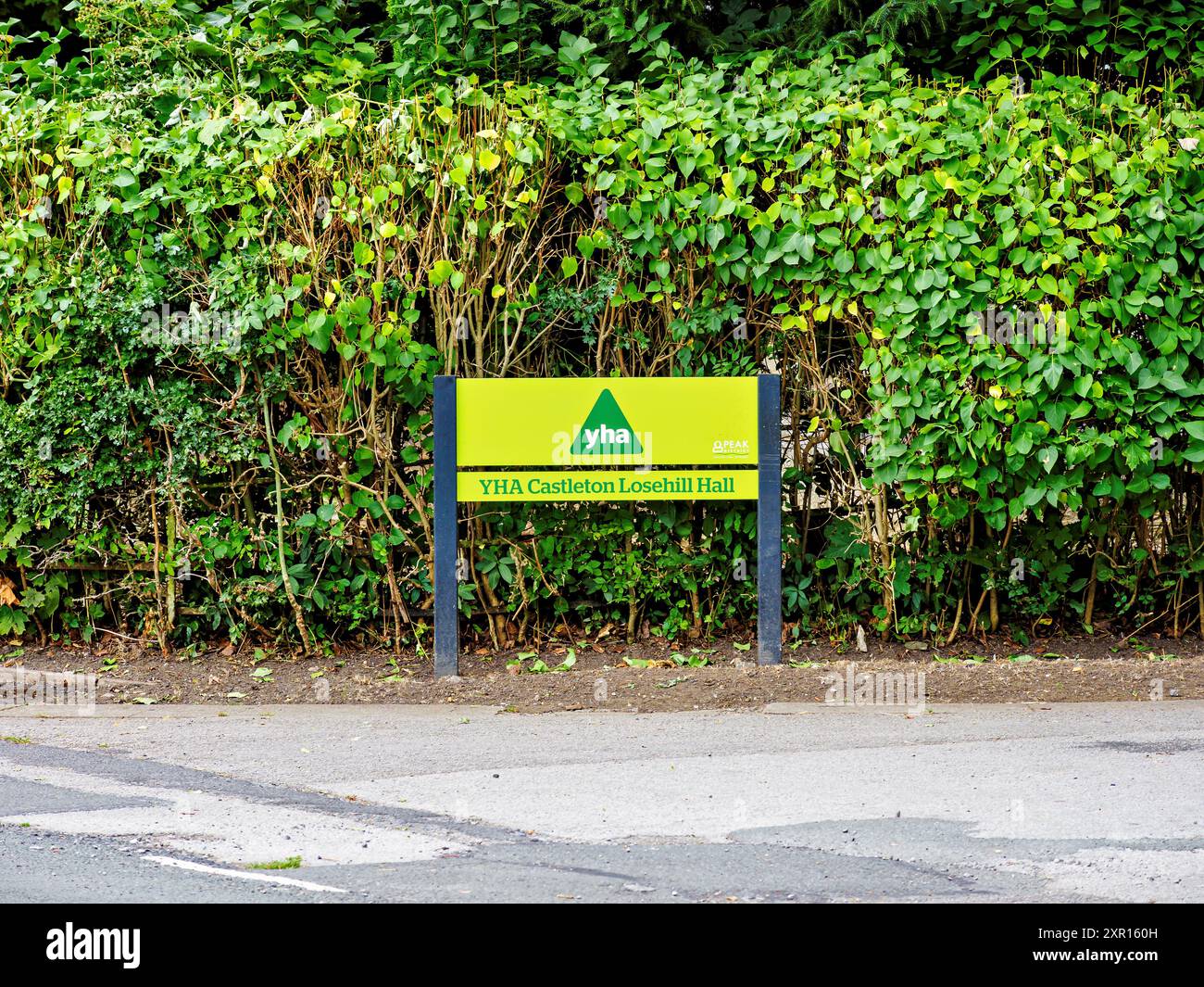 Entrance sign for hostel in front of lush green hedge, indicating YHA ...