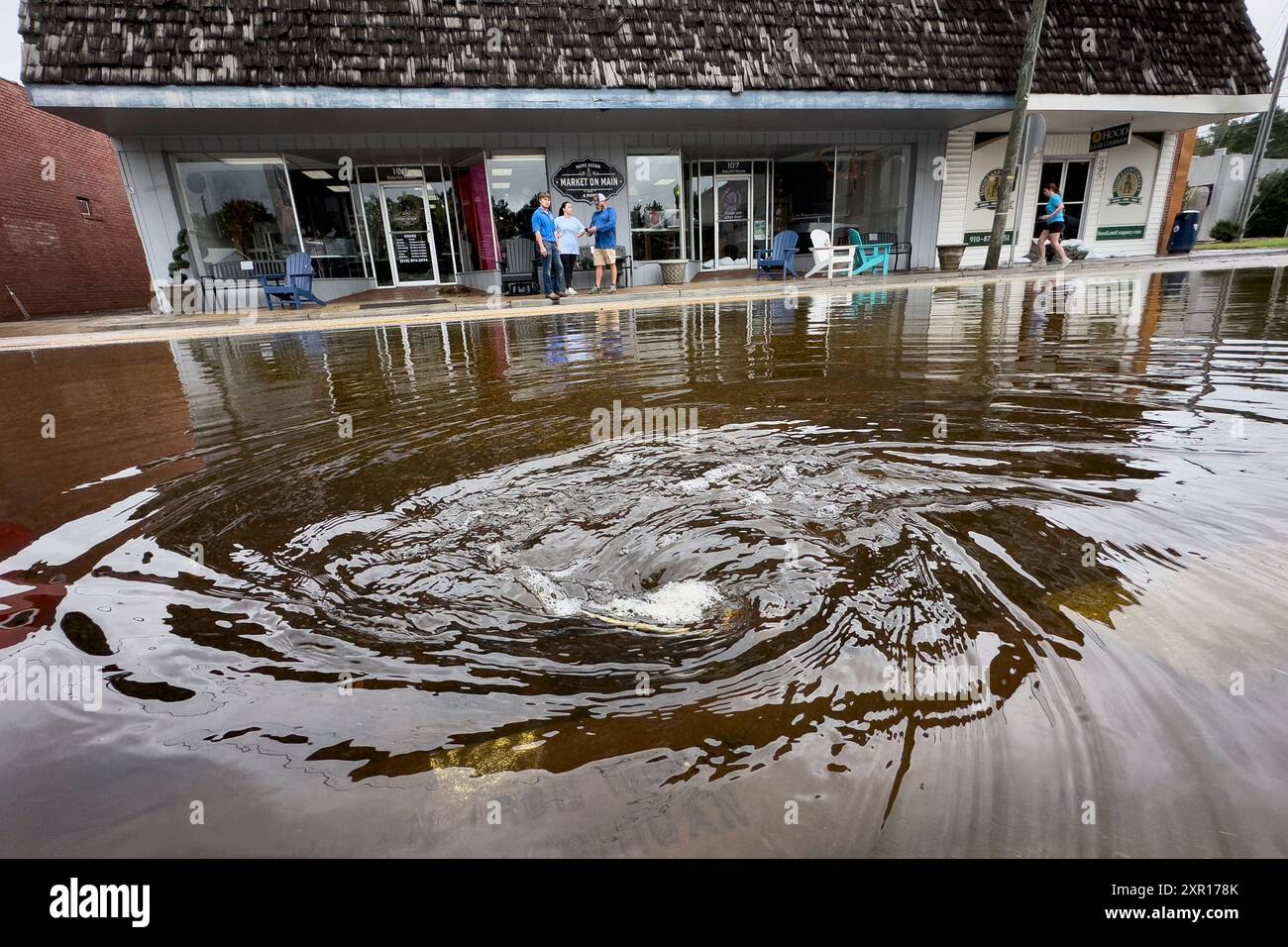 A drain pulls in residual rain water floods the downtown area caused by ...