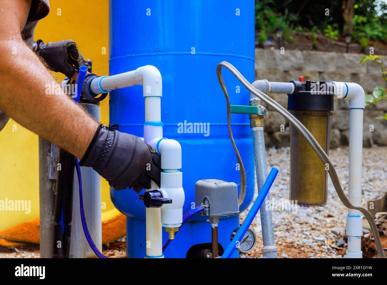 An artesian well system pump house is being connected to PVC water pipe ...