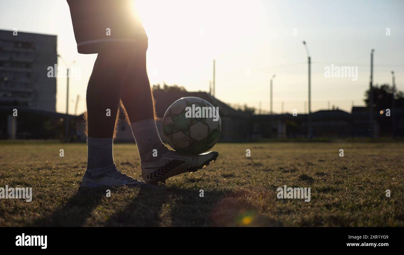 Legs of young man kicking ball at green field. Male feet of ...
