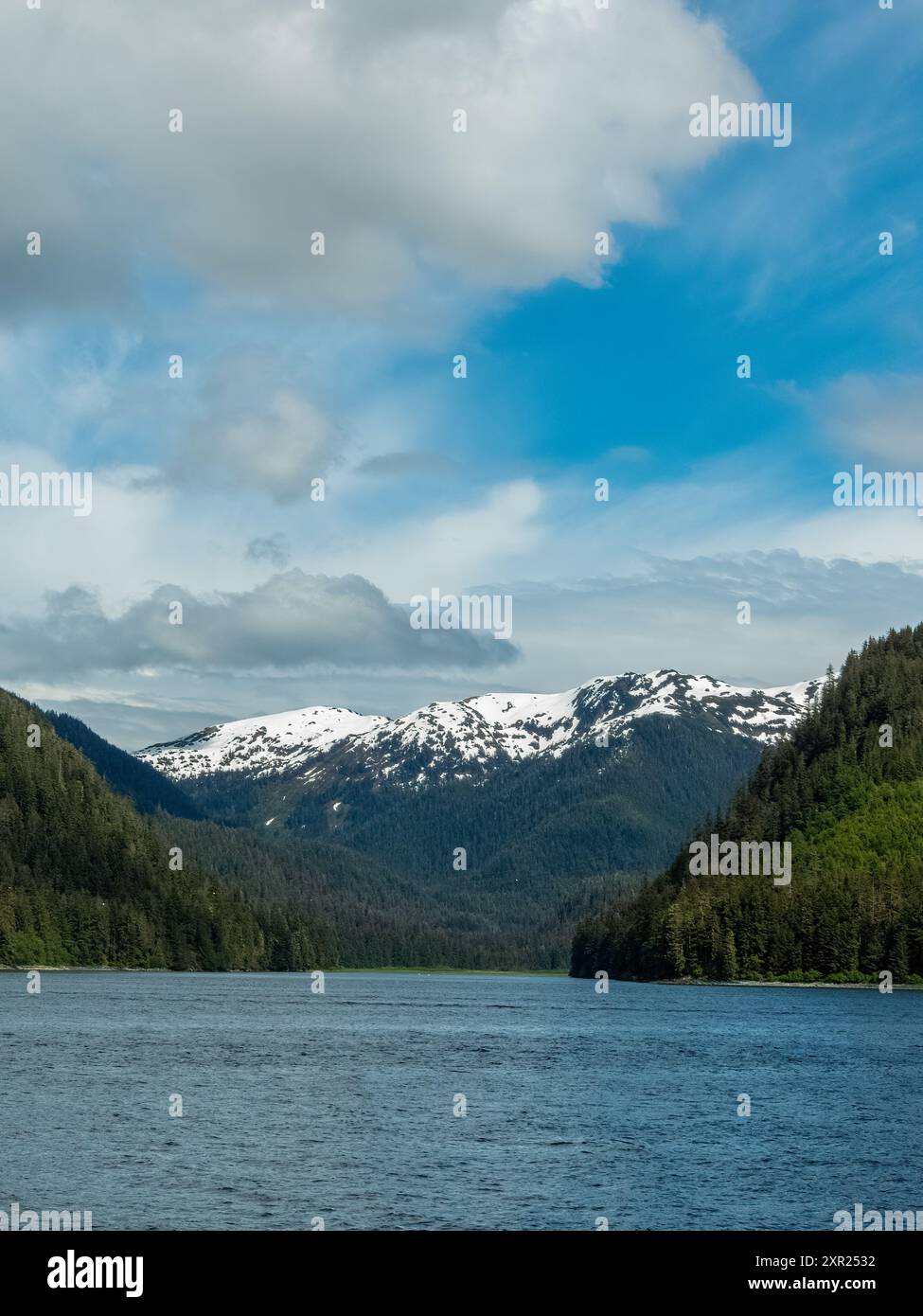 Water passage leading into a cove under blue sky and white clouds. Snow ...