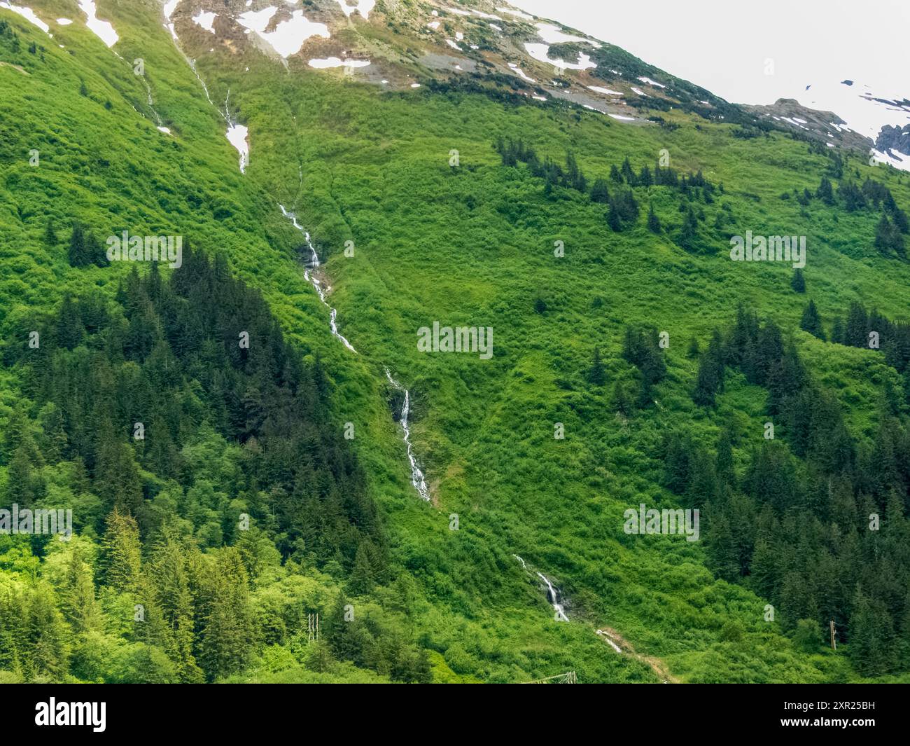 Small waterfall running down from the top of a snow topped mountain ...