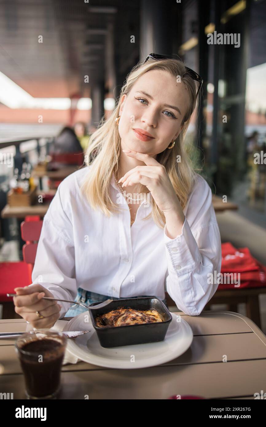 Blonde gen z woman eating lasagna in the cafe on break. Gen z girl ...