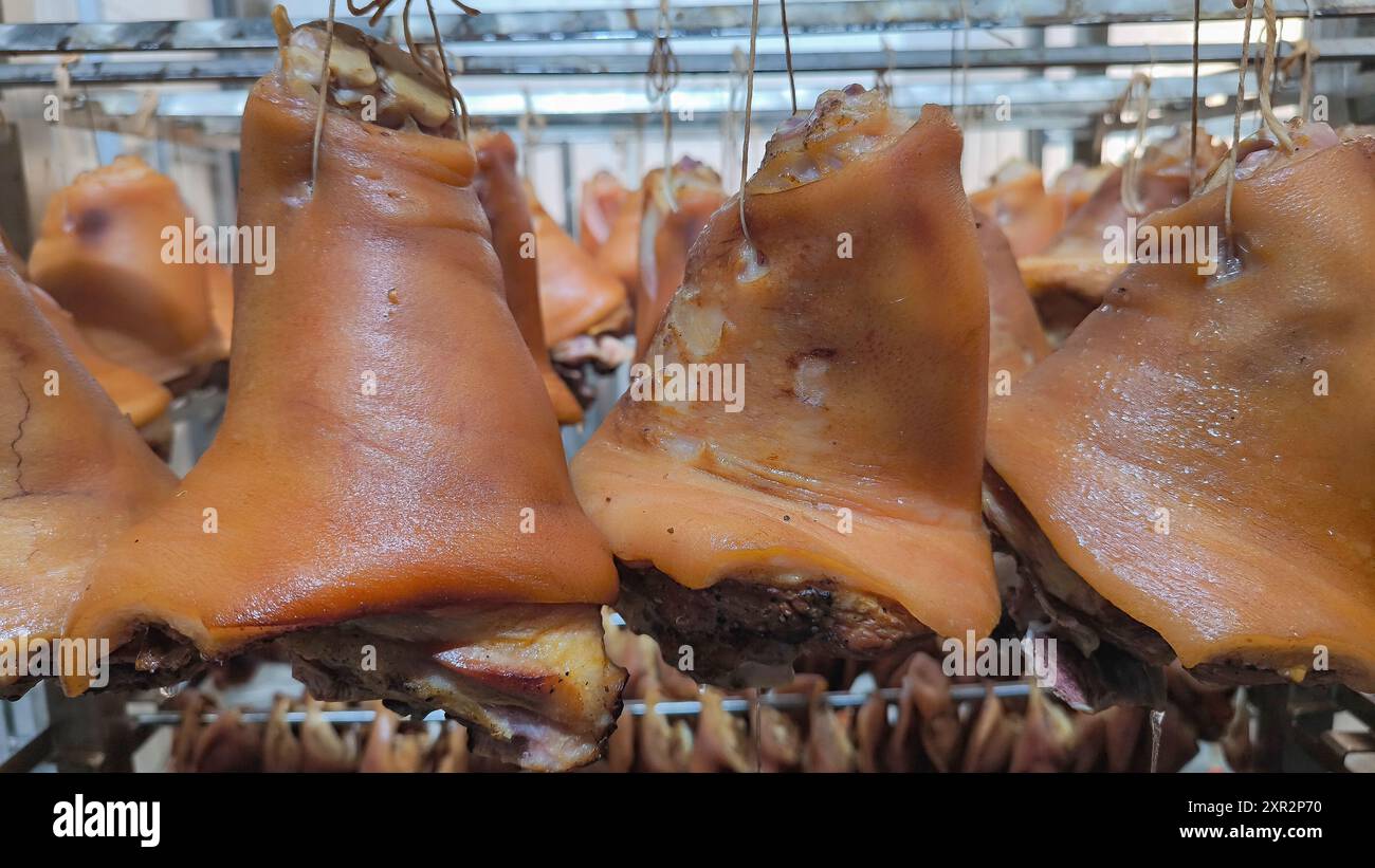 A close-up of dried pig's feet hanging in an industrial setting ...
