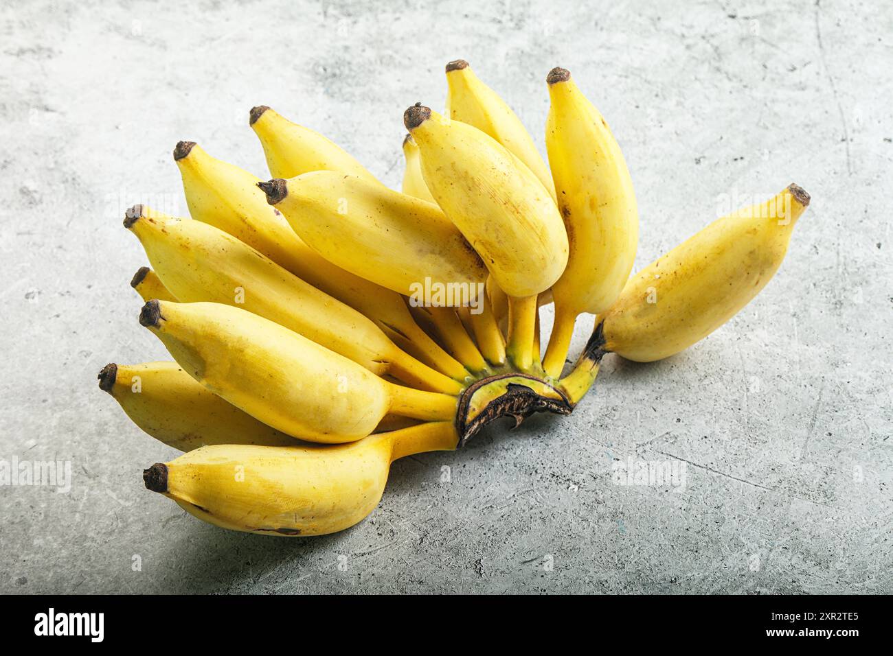 Small sweet ripe banana heap over background Stock Photo - Alamy