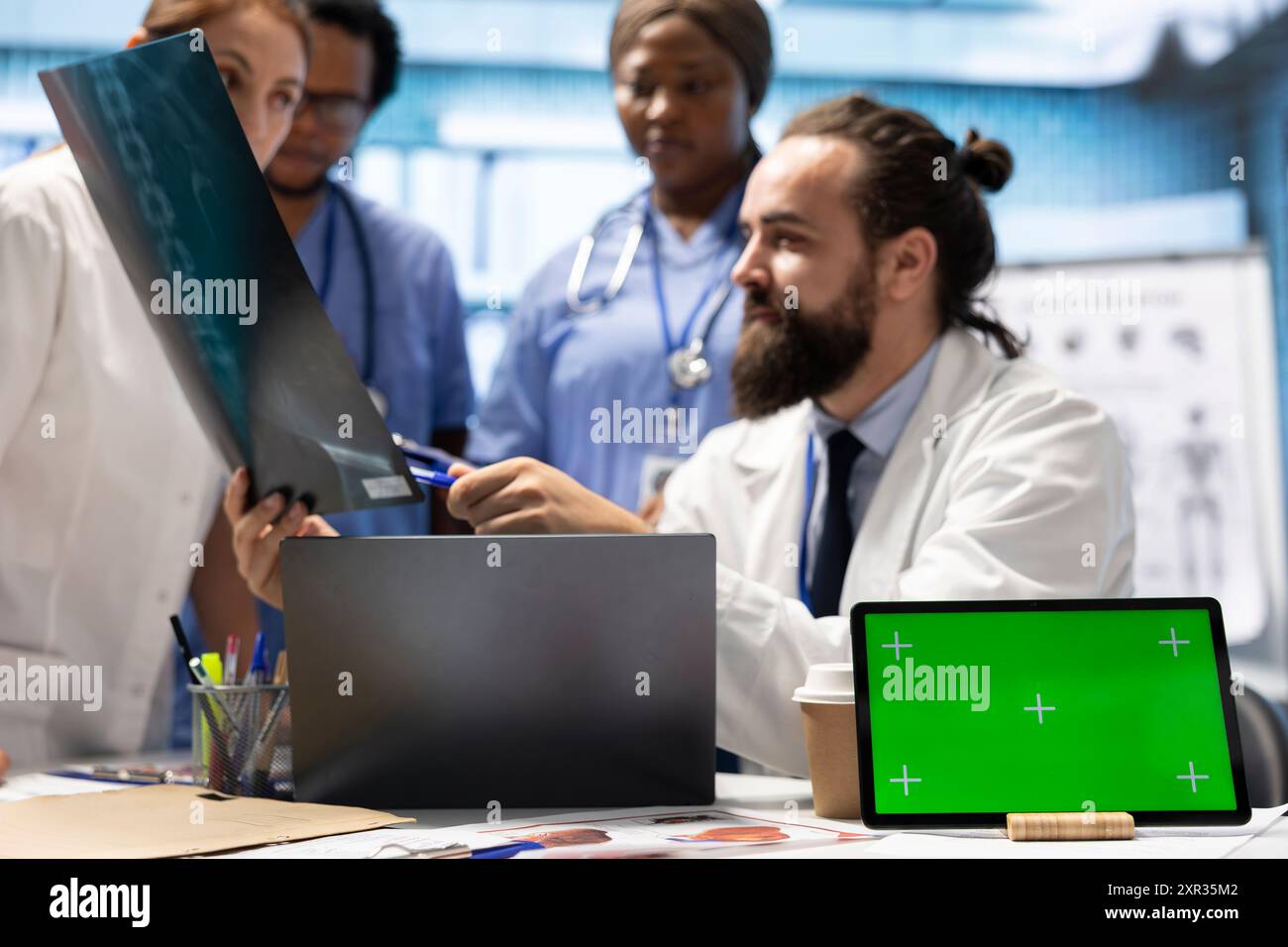 Doctors and nurses review radiography scans with a green screen on desk ...