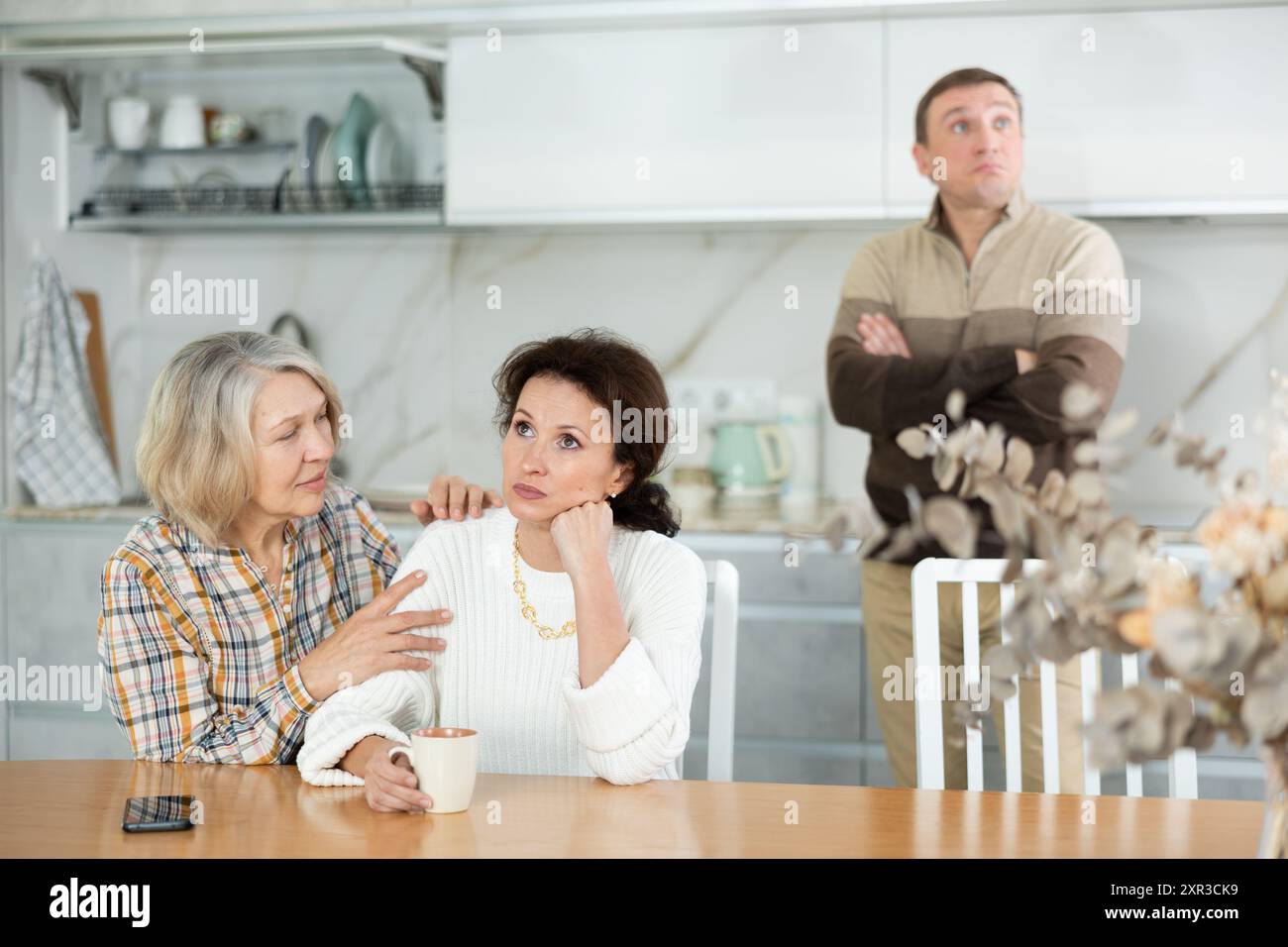 Family members quarreling in the kitchen and old woman trying to calm ...