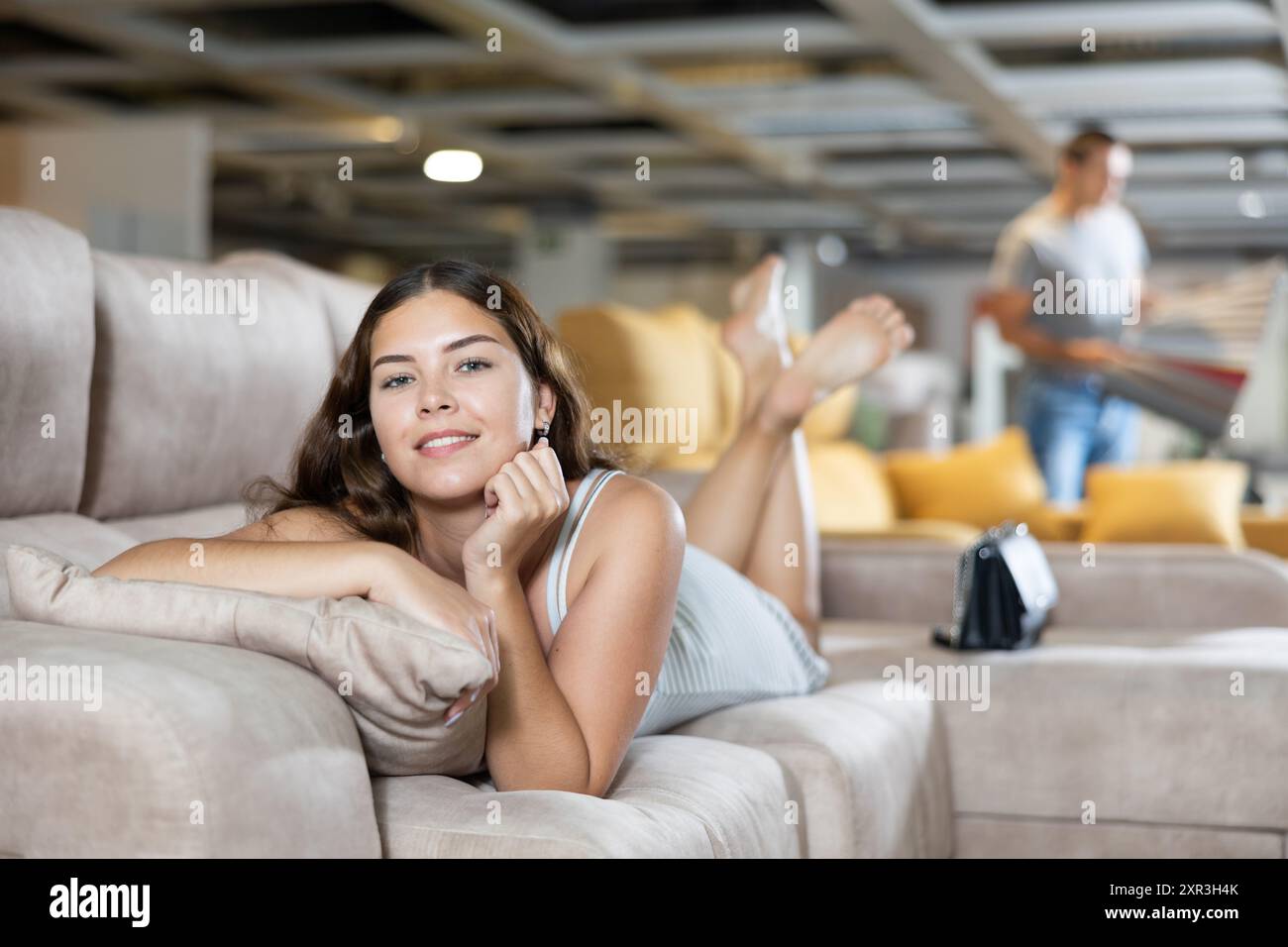 On sofa girl is lying on stomach with chin propped up in hands in ...