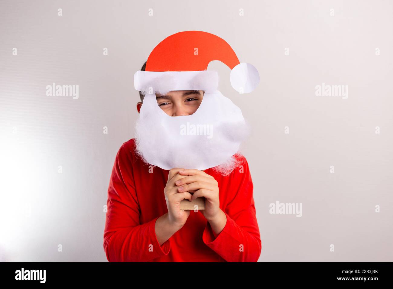 Christmas time - a boy wearing a paper craft Santa hat and beard ...