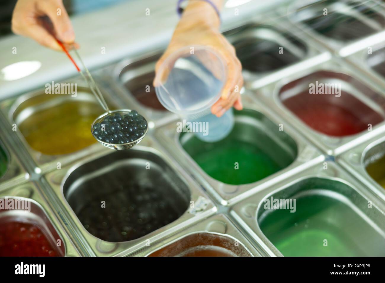 Making bubble tea in cafe. Metal containers with colorful tapioca balls ...