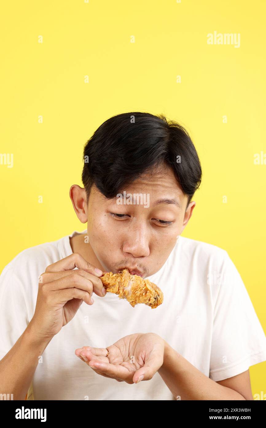 Indonesian Man Eating Crispy Fried Chicken Leg Drumstick on Yellow ...