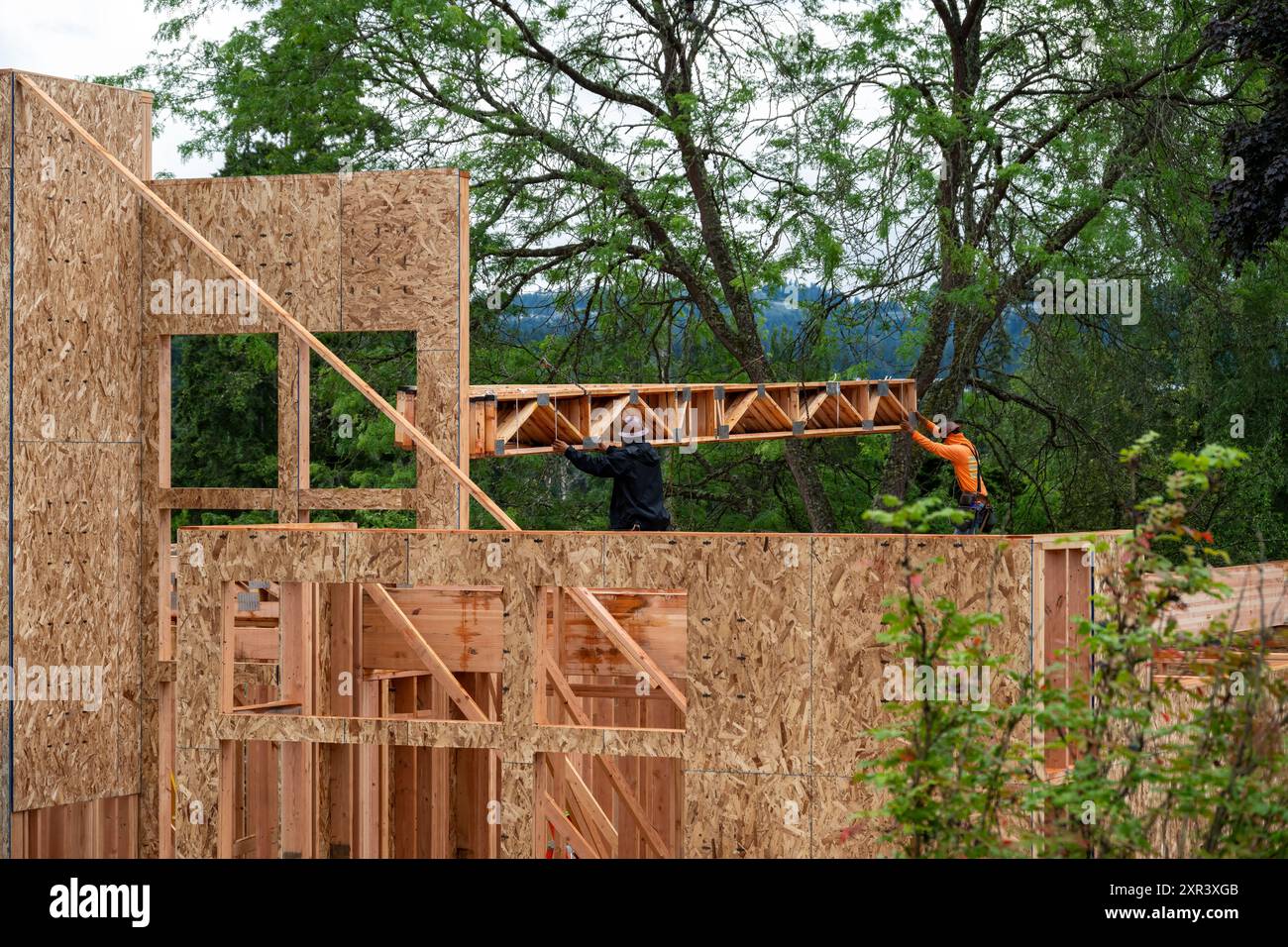 Residential house construction, boom crane lifting lumber delivery ...