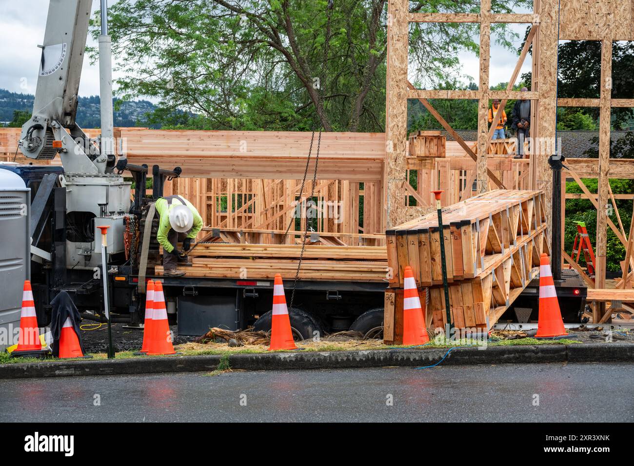 Residential house construction, boom crane truck delivering lumber to job site, wood support ...
