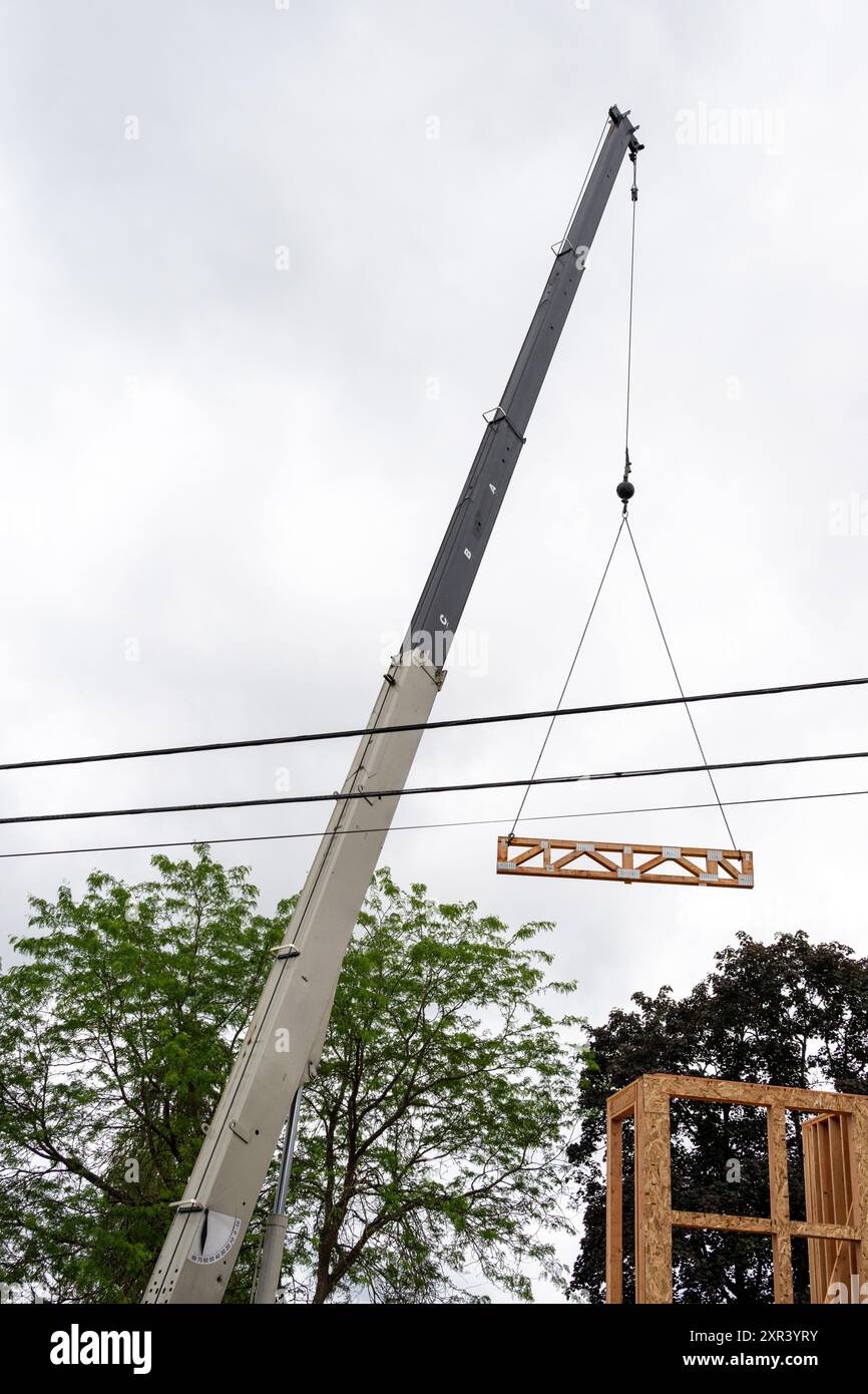 Residential house construction, boom crane lifting lumber delivery ...