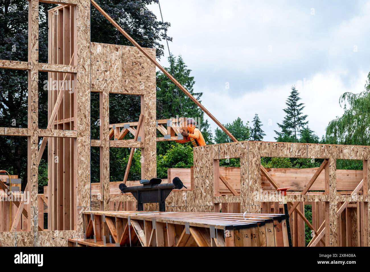 Residential house construction, boom crane lifting lumber delivery ...