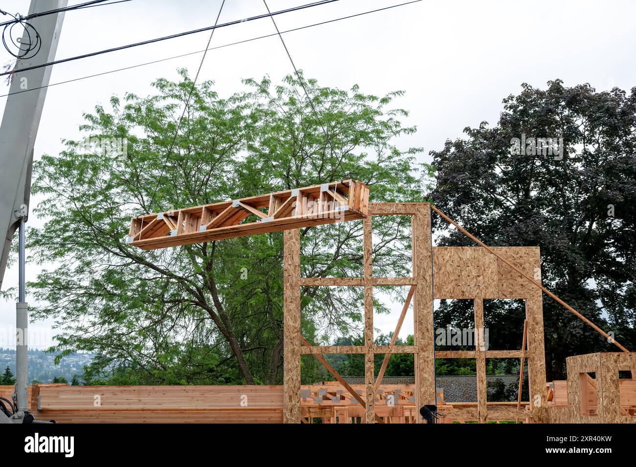 Residential house construction, boom crane lifting lumber delivery ...
