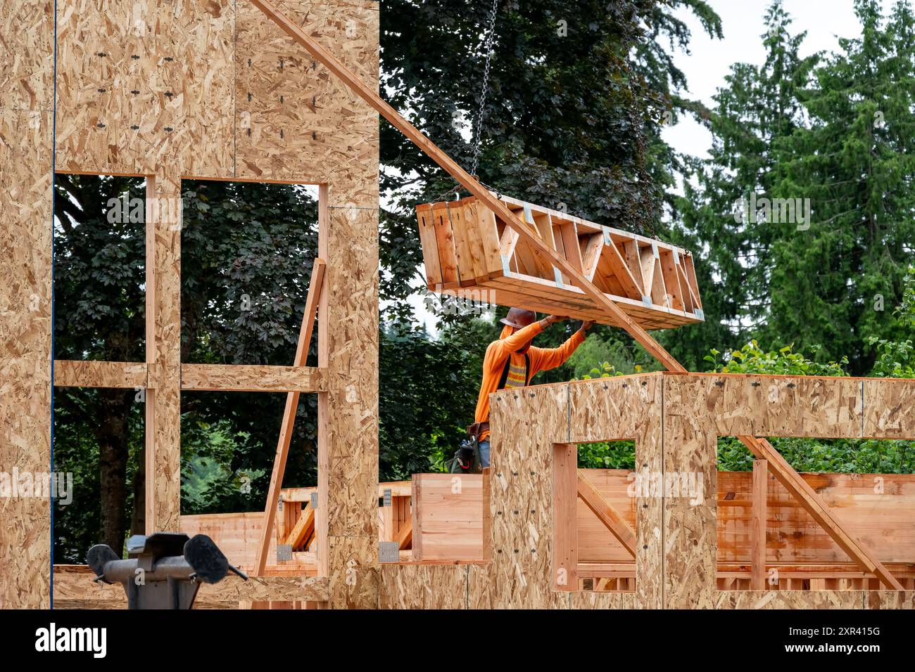 Residential house construction, boom crane lifting lumber delivery ...