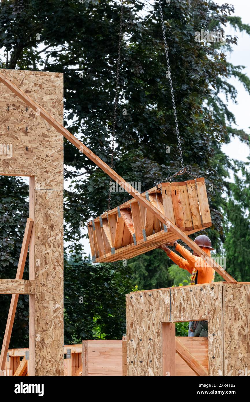 Residential house construction, boom crane lifting lumber delivery ...