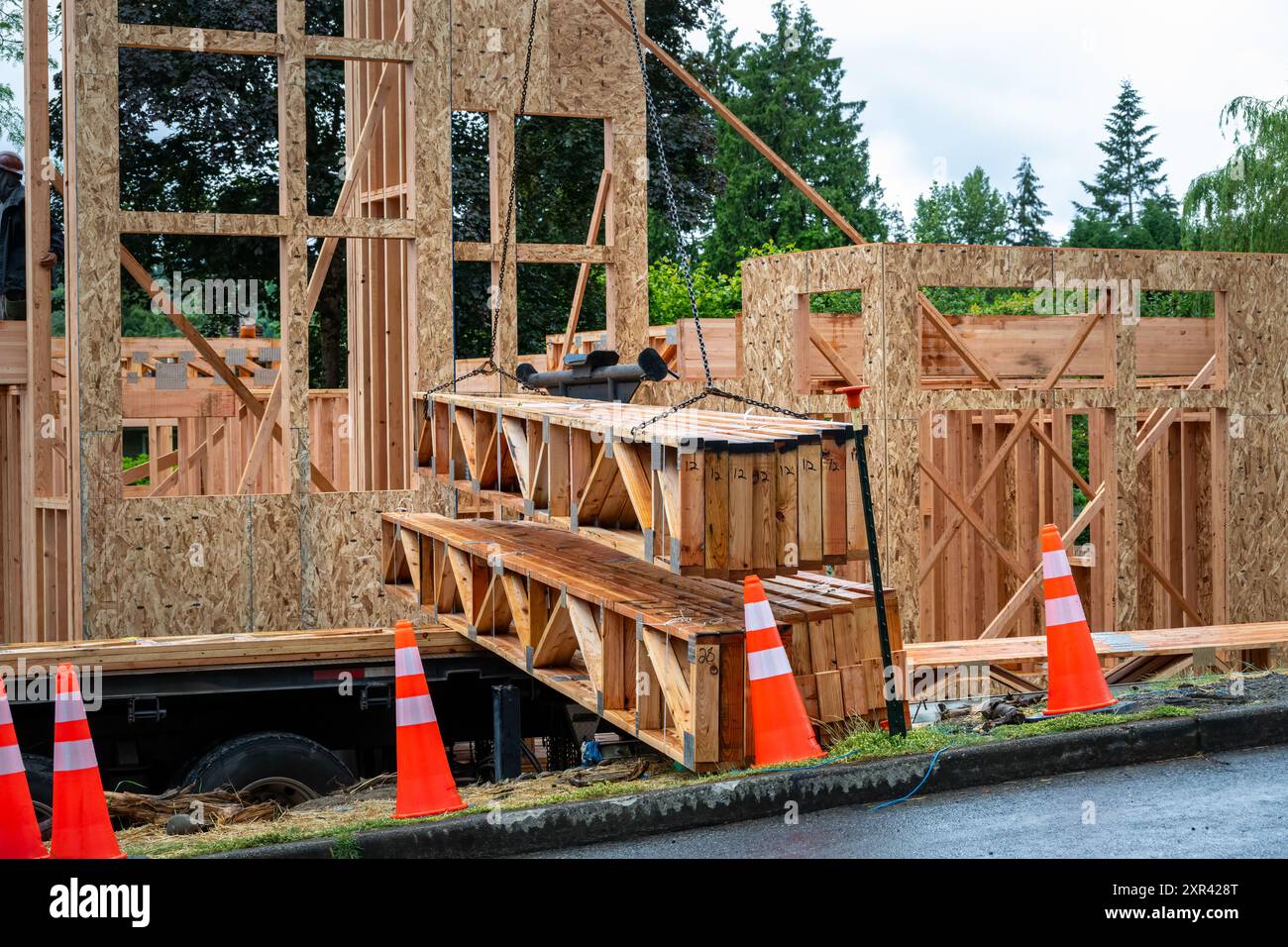 Residential house construction, boom crane lifting lumber delivery ...