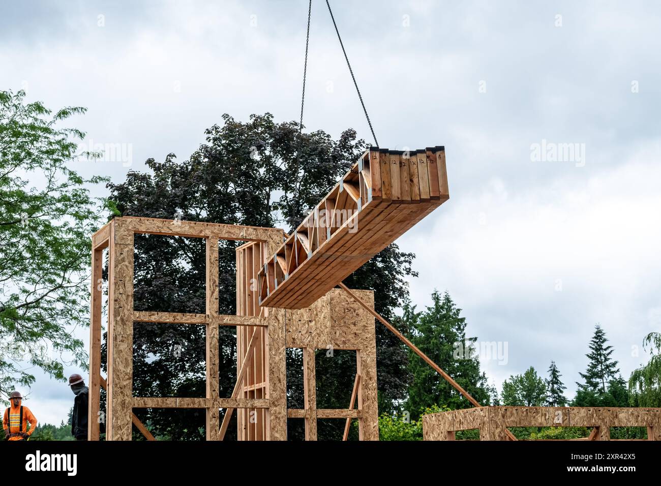 Residential house construction, boom crane lifting lumber delivery ...