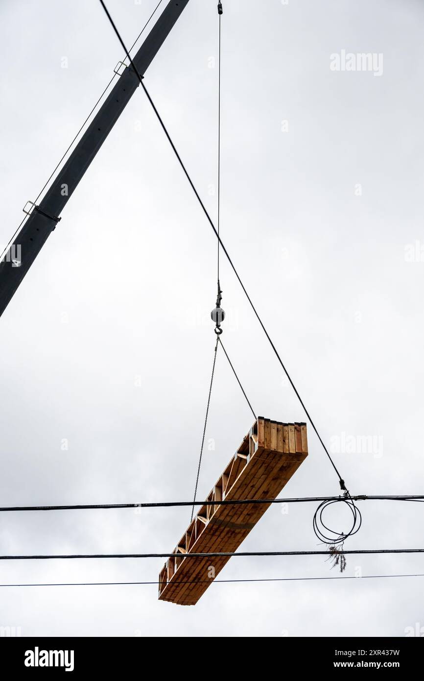 Residential house construction, boom crane lifting lumber delivery ...