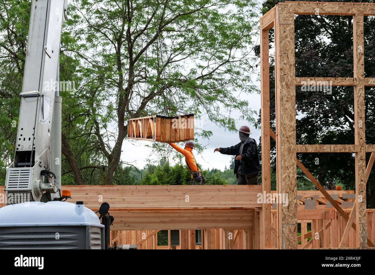 Residential house construction, boom crane lifting lumber delivery ...