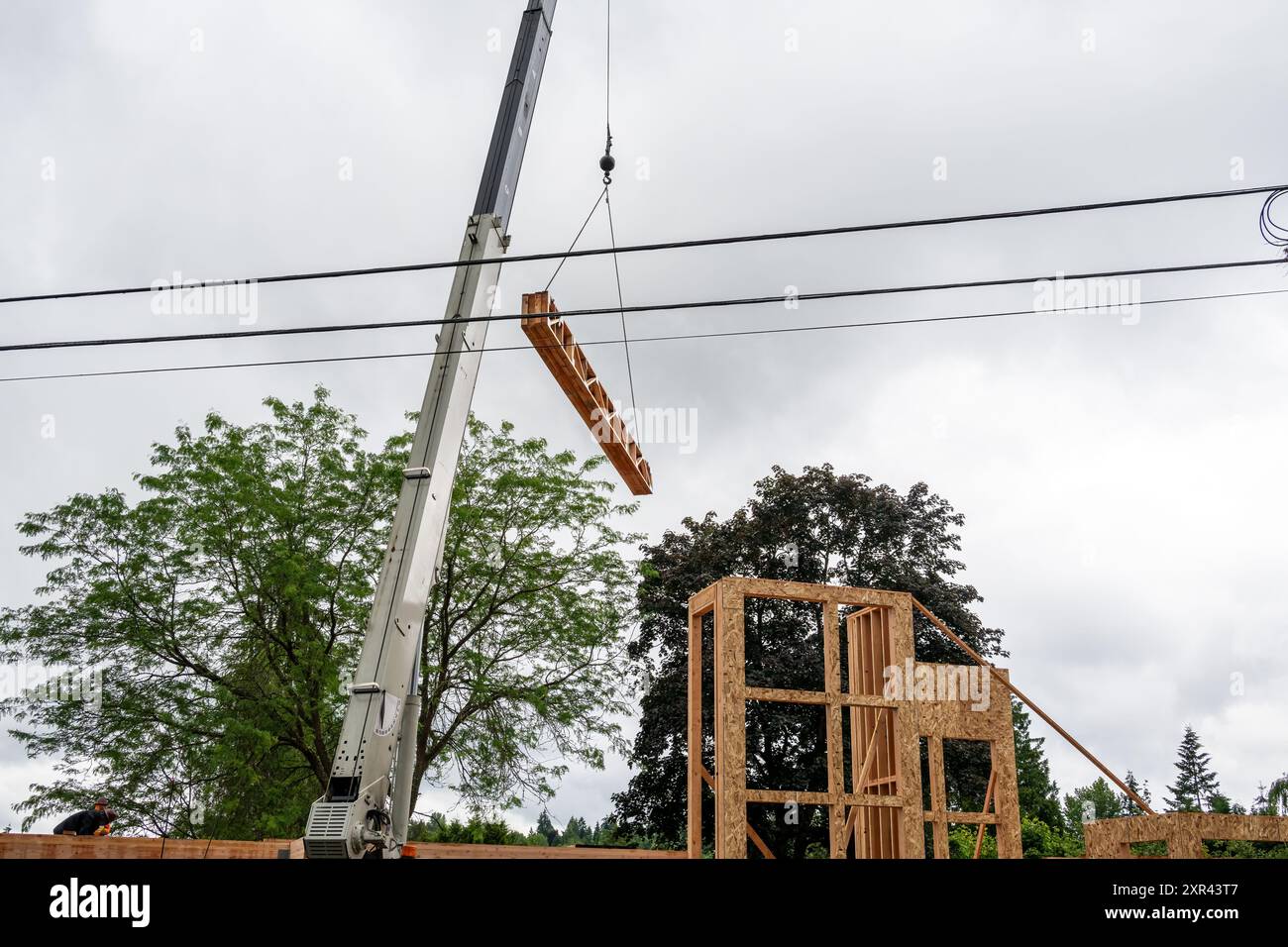 Residential house construction, boom crane lifting lumber delivery ...
