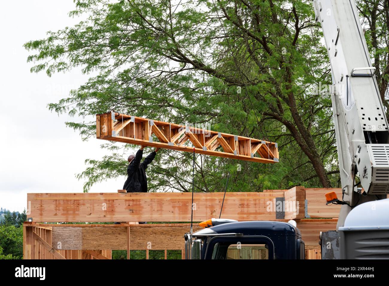 Residential house construction, boom crane lifting lumber delivery ...