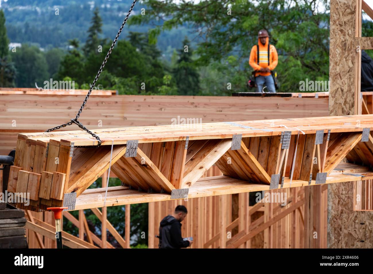 Residential house construction, boom crane lifting lumber delivery ...