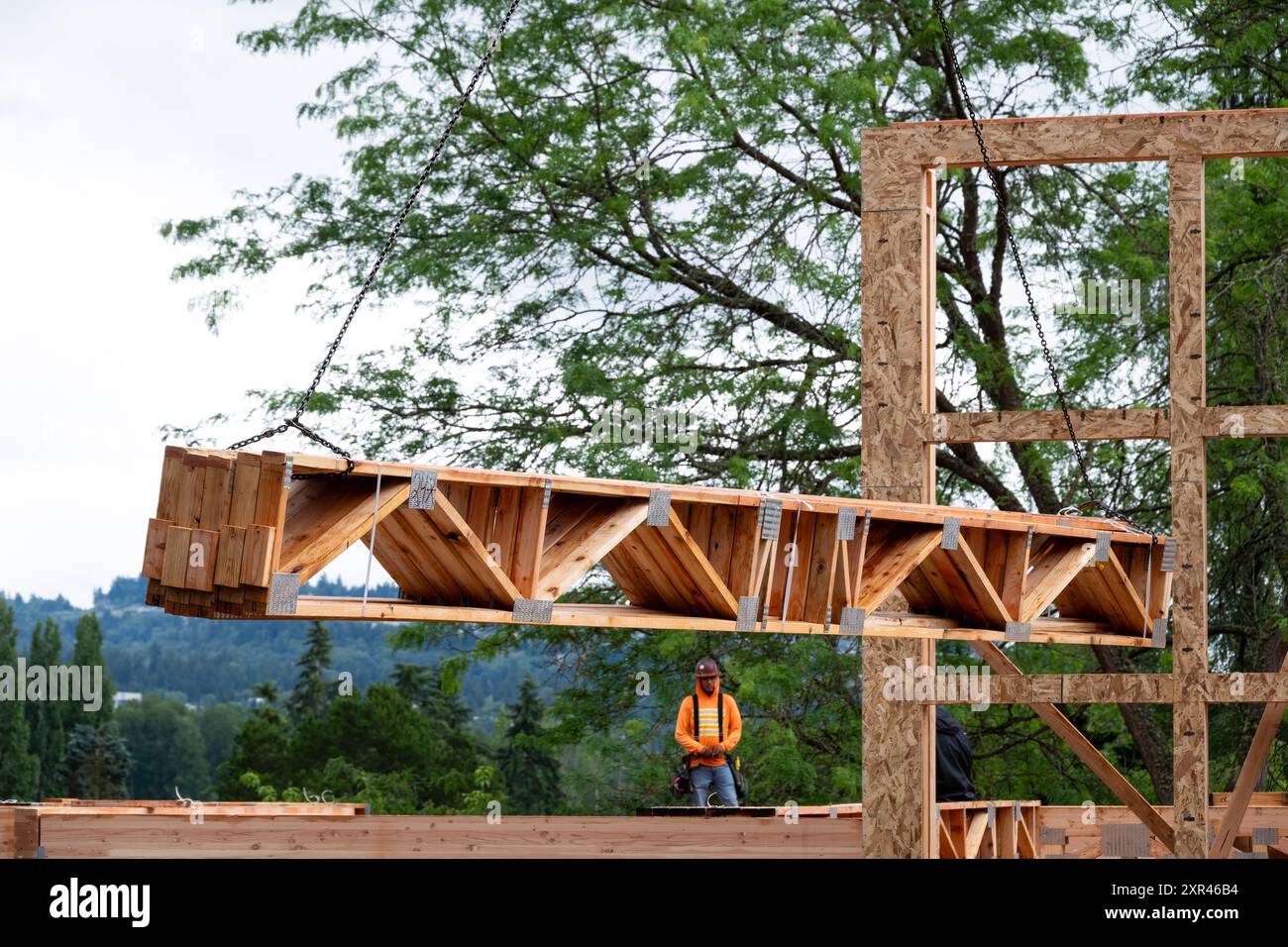 Residential house construction, boom crane lifting lumber delivery ...