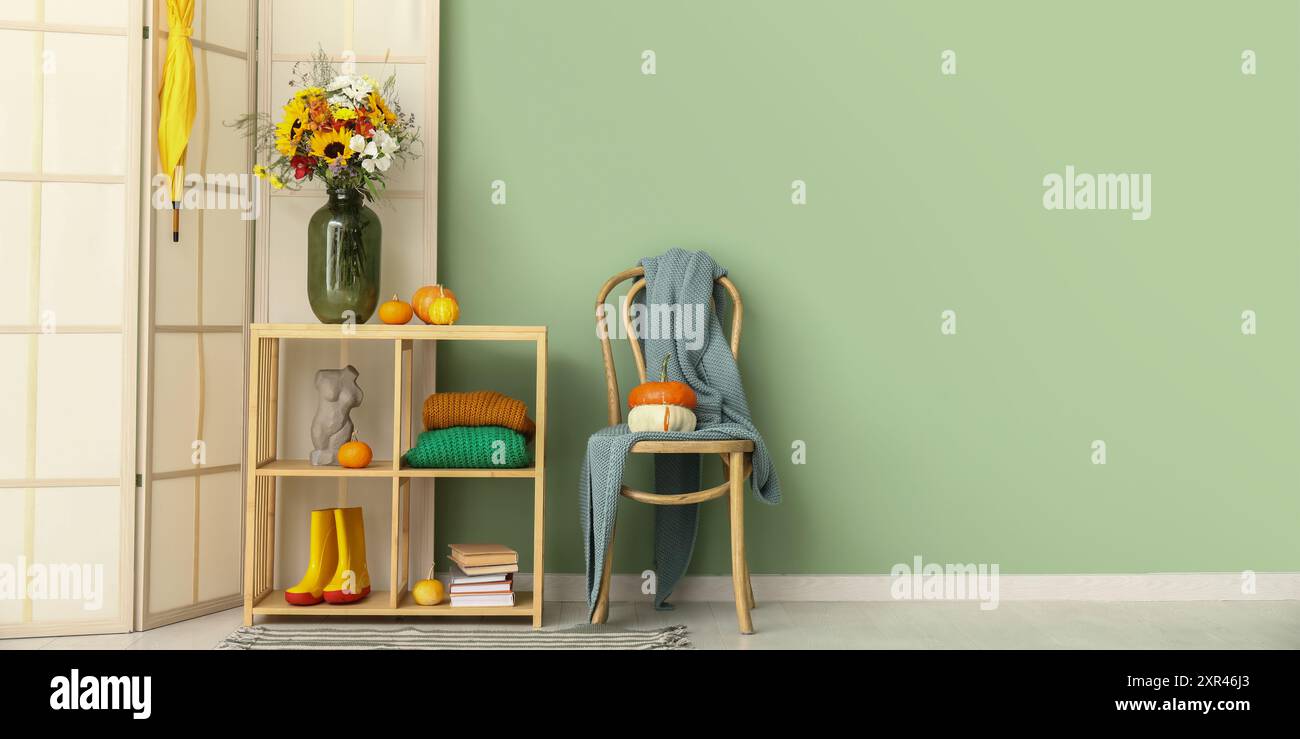 Shelving unit with bouquet of autumn flowers, folding screen and chair ...