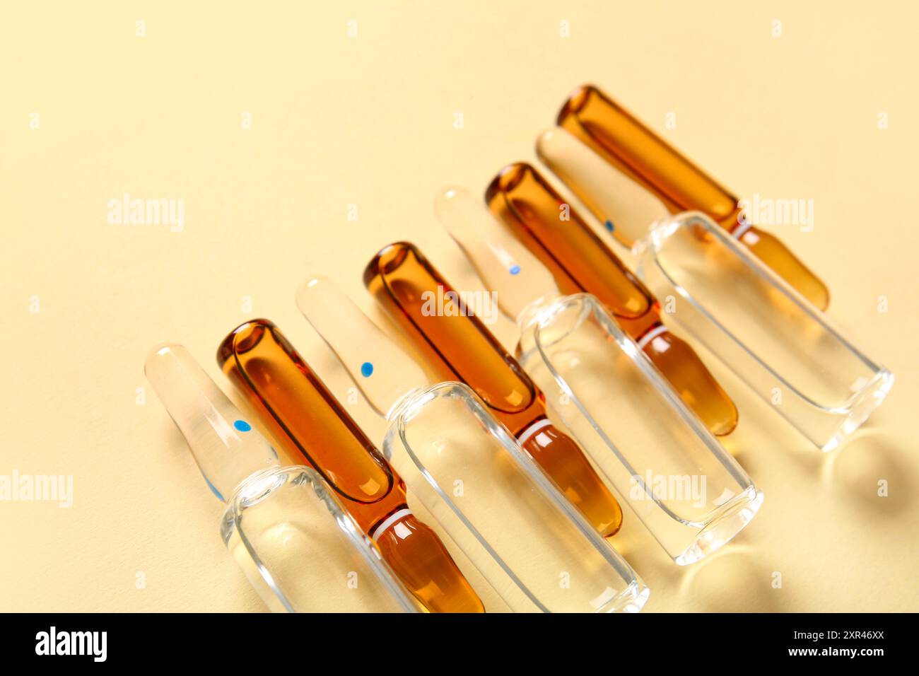 Glass medical ampules on light yellow background Stock Photo - Alamy
