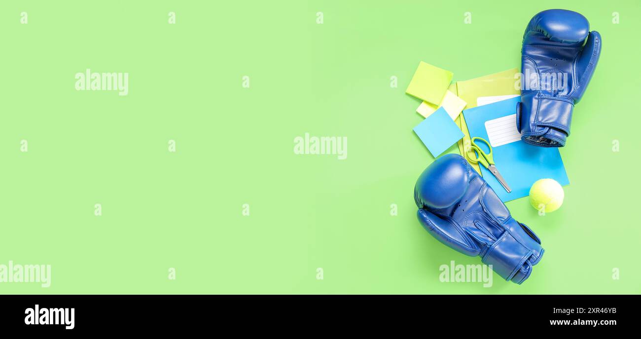 Boxing gloves with tennis ball and school stationery on green ...