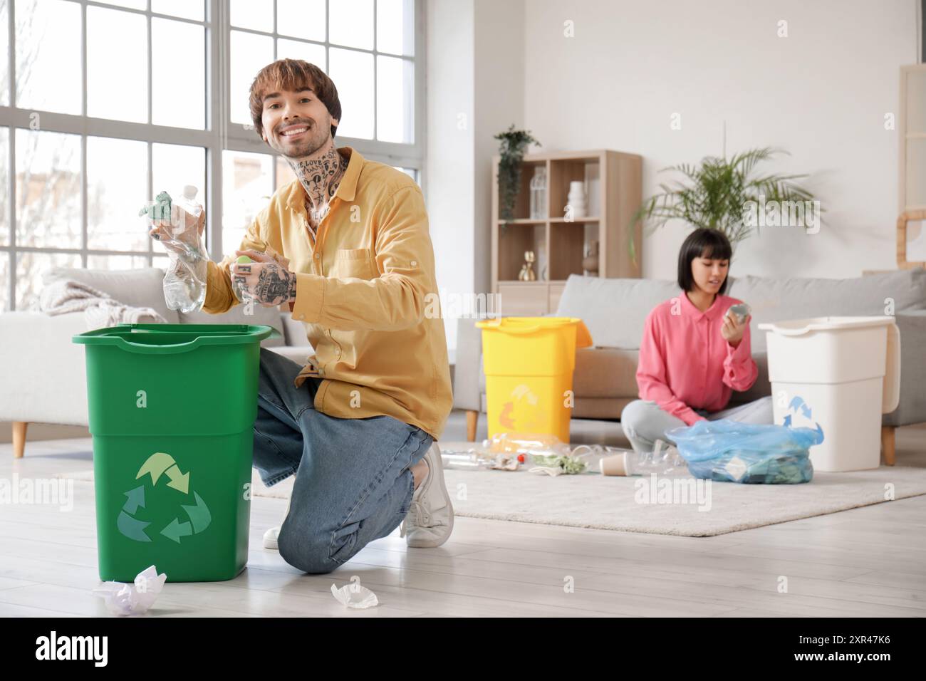 Young couple with garbage containers sorting rubbish in living room ...