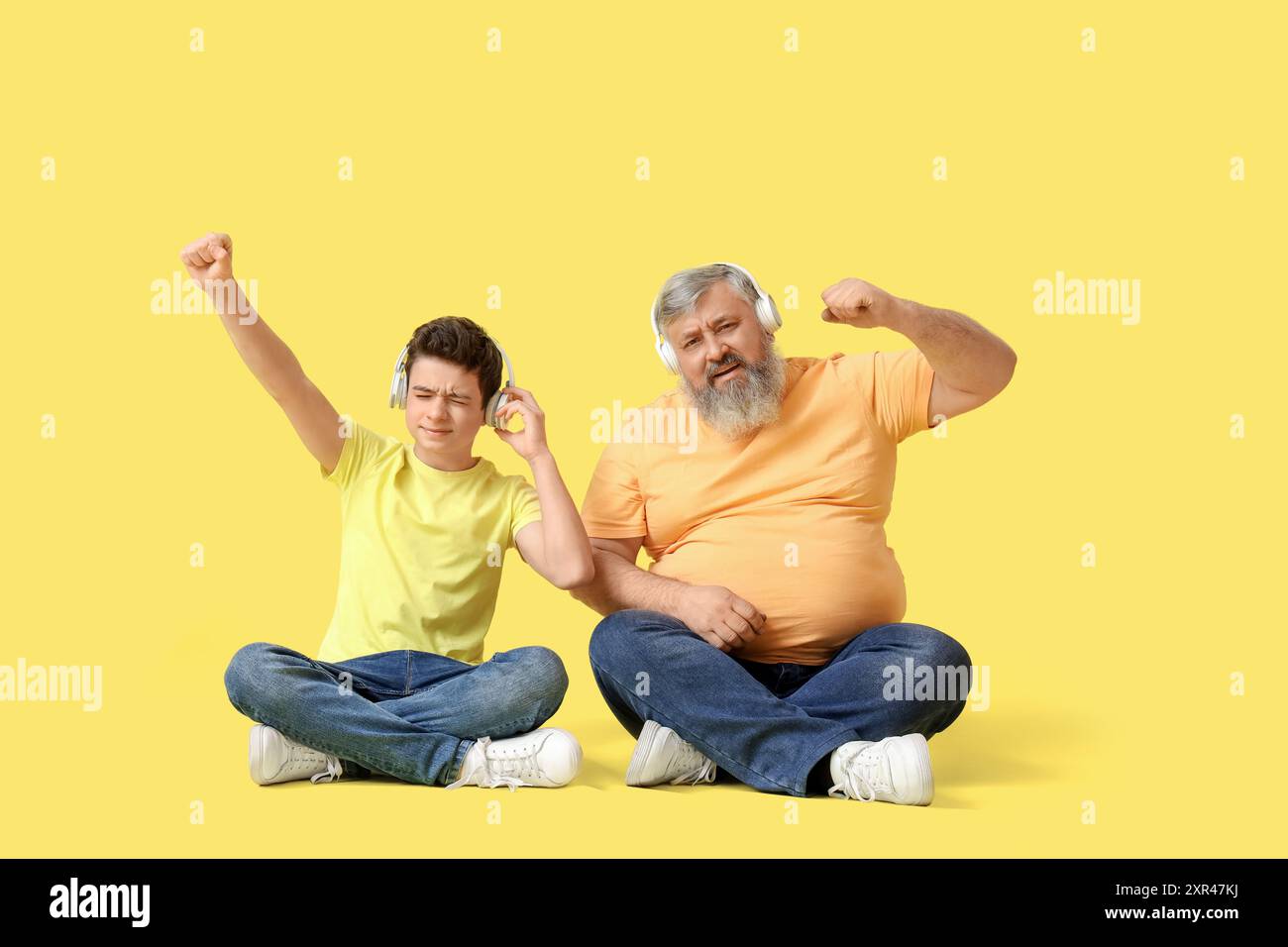 Happy grandfather with his cute grandson in headphones listening music ...
