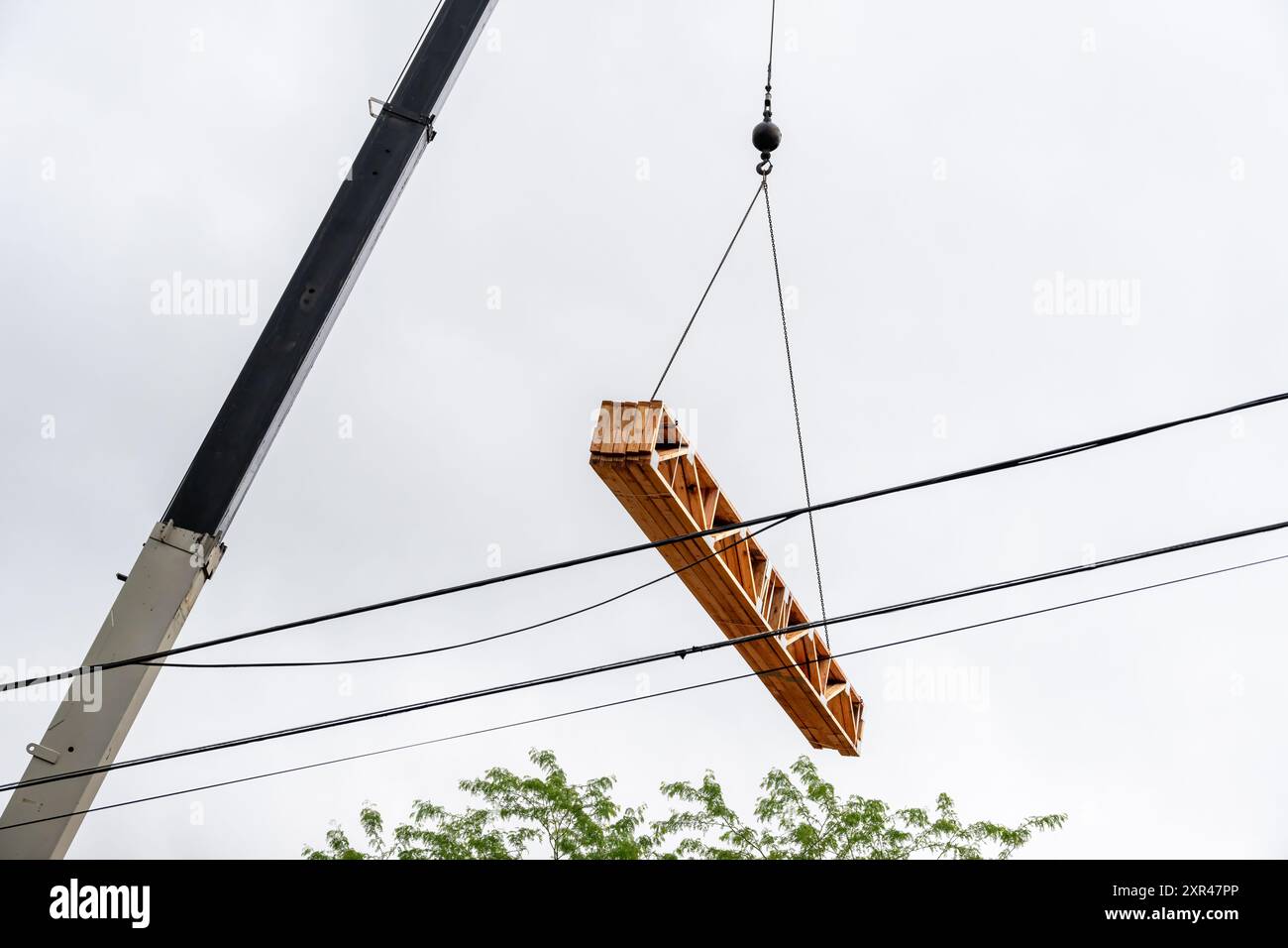 Residential house construction, boom crane lifting lumber delivery ...