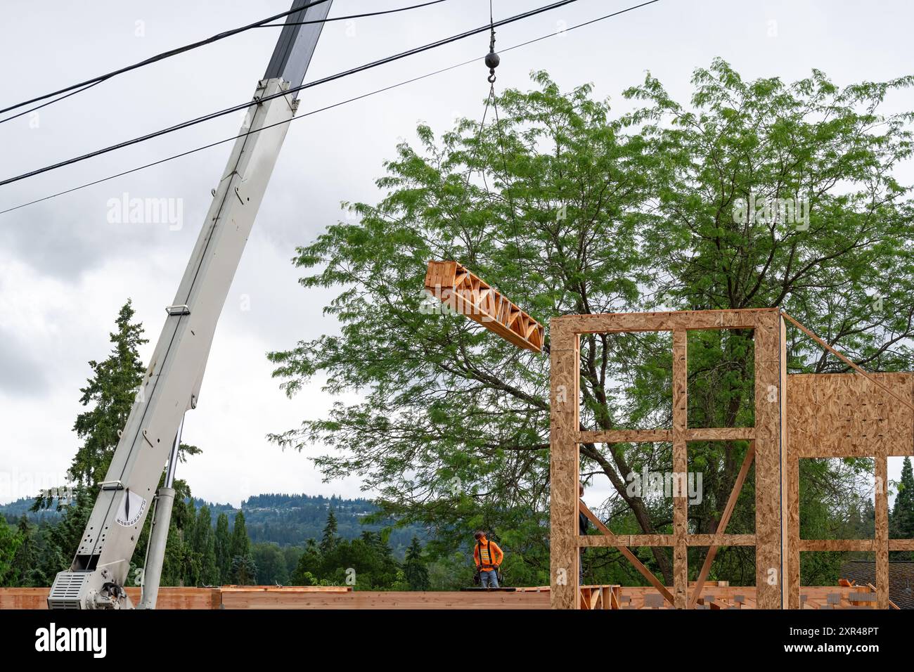 Residential house construction, boom crane lifting lumber delivery ...